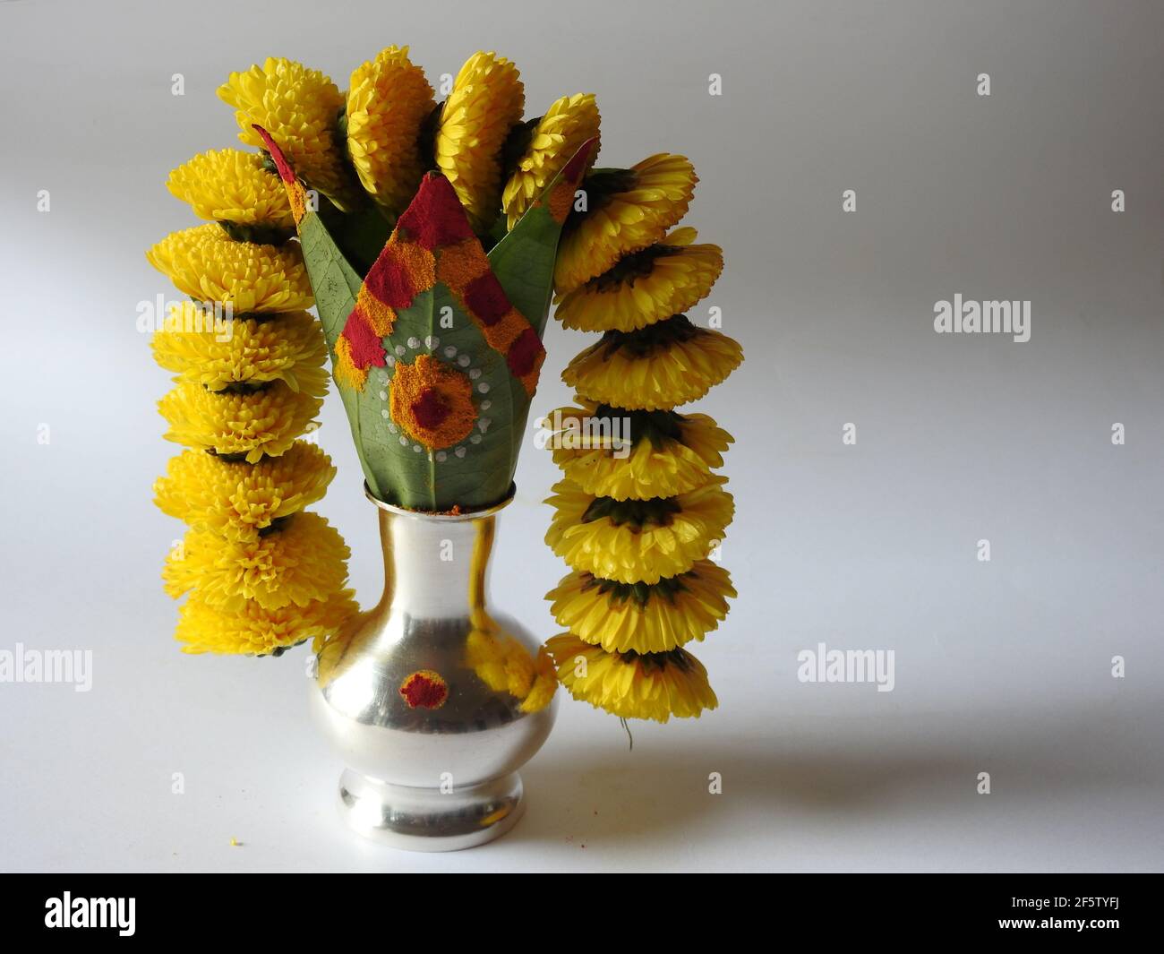 A silver Kalash with chrysanthemum flowers, leaves, kumkum, turmeric ...