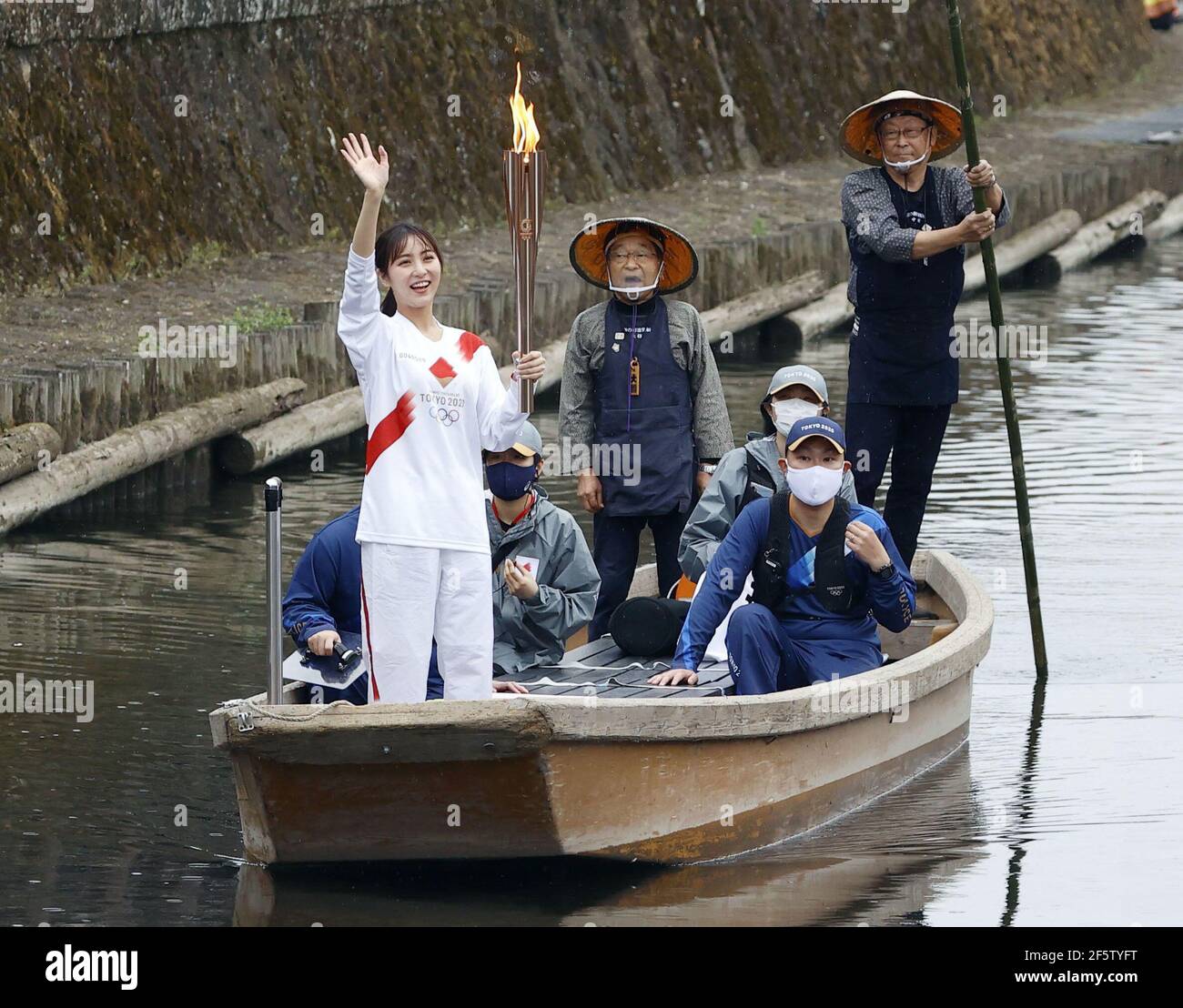 The Tokyo Olympic torch is carried aboard a boat as part of its relay ...