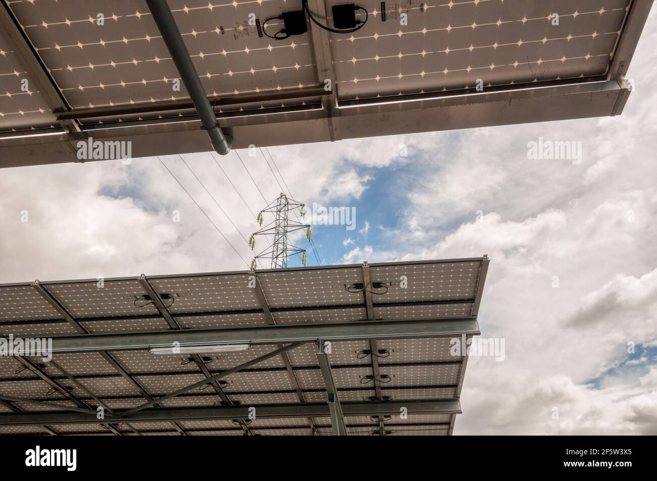 Overhead electricity line & transmission tower seen from below an array ...