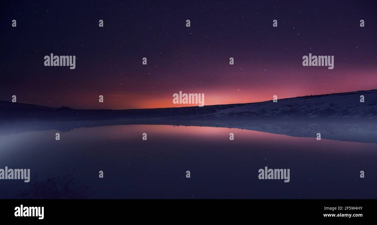 Morning dawn on a starry background sky reflected in the water of the ...
