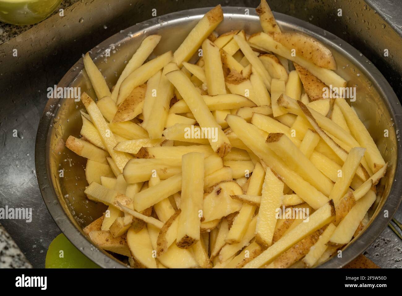 A top view of fresh raw sliced french fries in a deep metal utensil ...