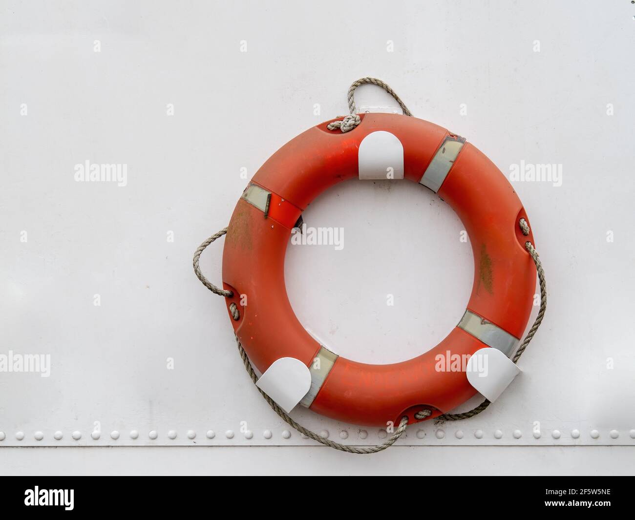 Real orange color lifebuoy hanging on white boat background Stock Photo ...