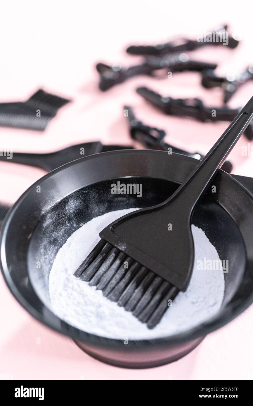 Hair color dye powder in a black plastic mixing bowl on a pink ...