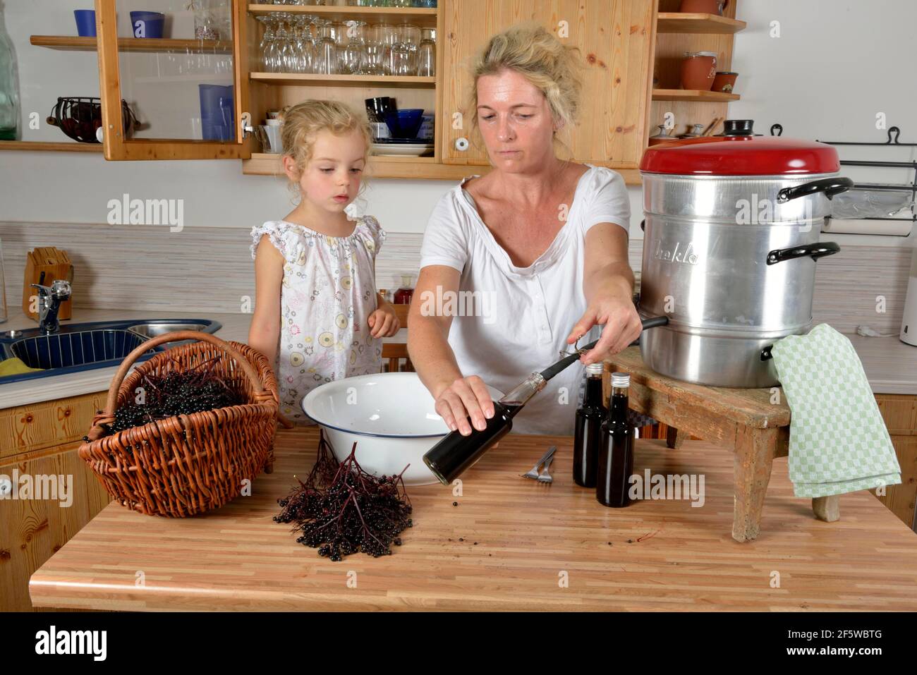 Woman and girl cooking elderberry juice (Sambucus nigra) (Sambuci ...