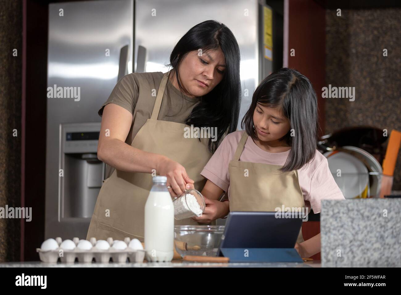 A Mexican mother teaching her daughter cooking in the kitchen Stock ...