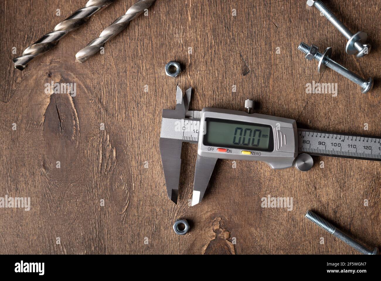 Digital caliper on wooden table with hardware Stock Photo - Alamy