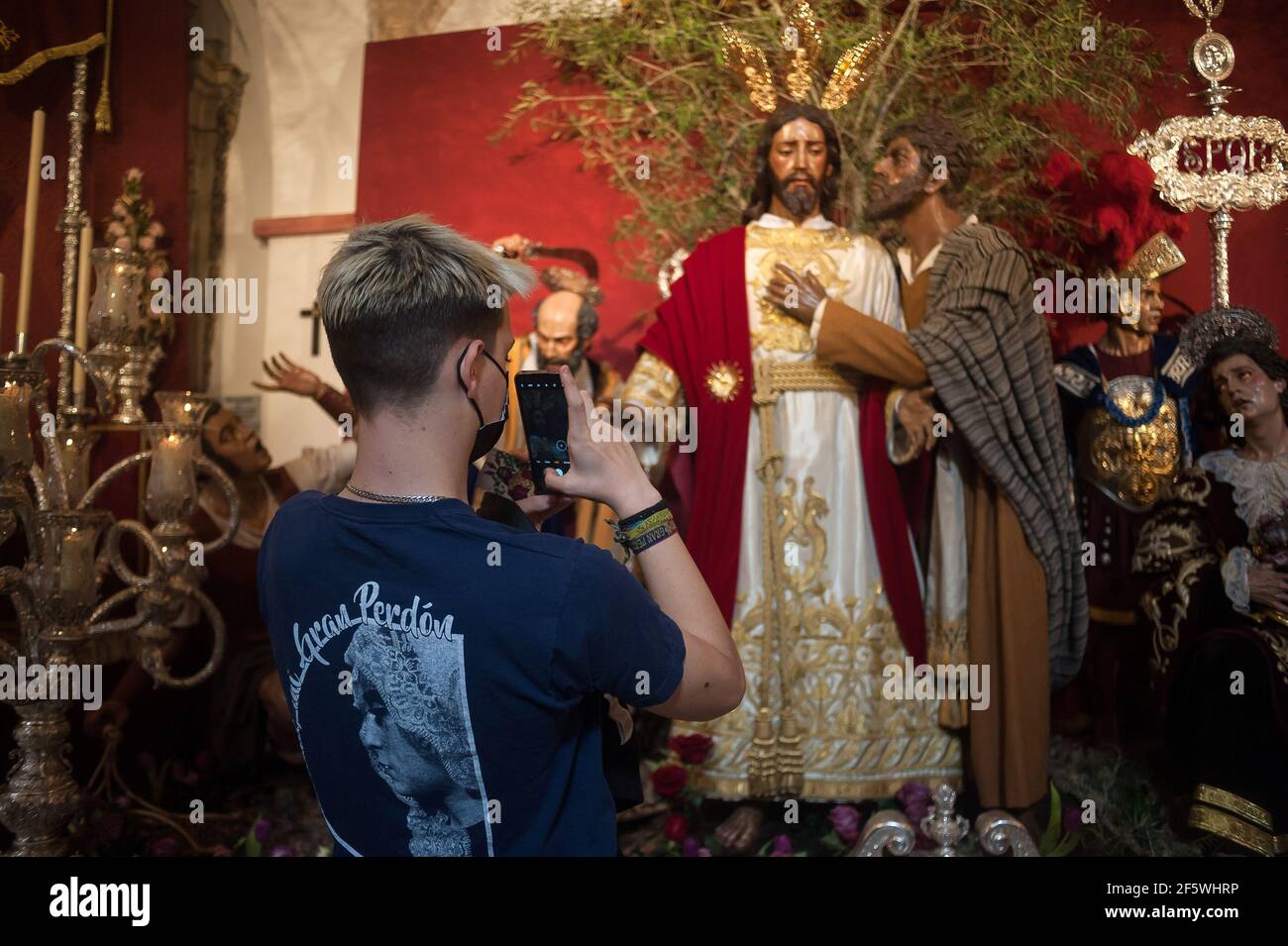 Malaga, Spain. 28th Mar, 2021. A believer wearing a face mask takes a ...