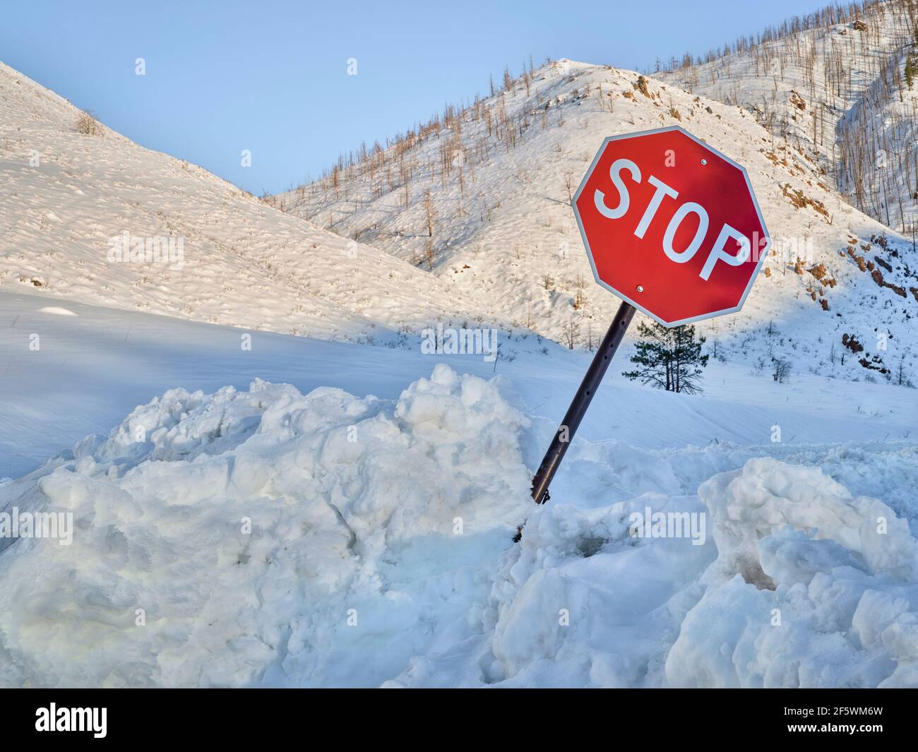 stop sign on a mountain highway after heavy snowstorm and snow plowing ...