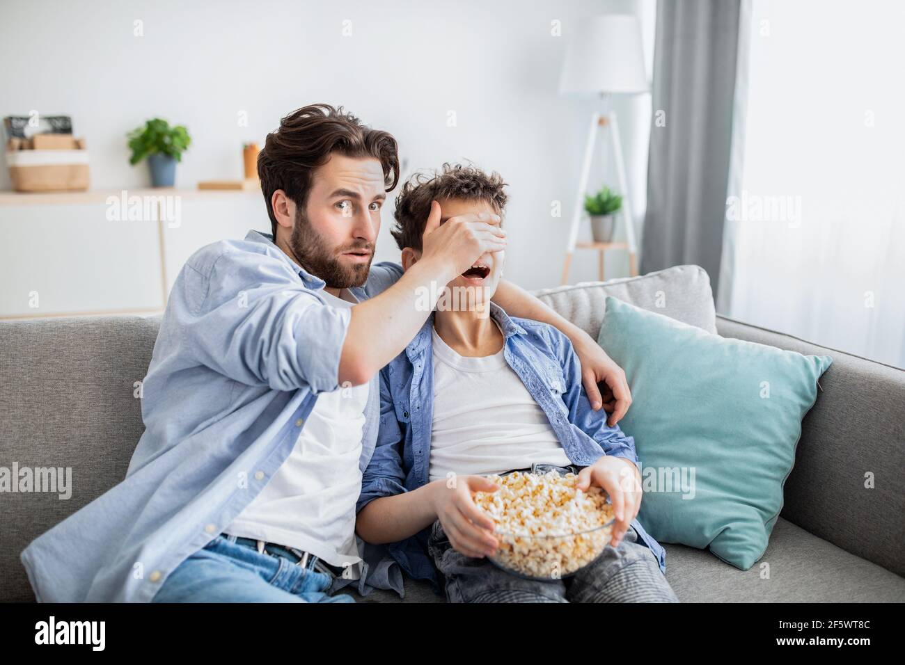 Father covering his son's eyes from inappropriate content while ...