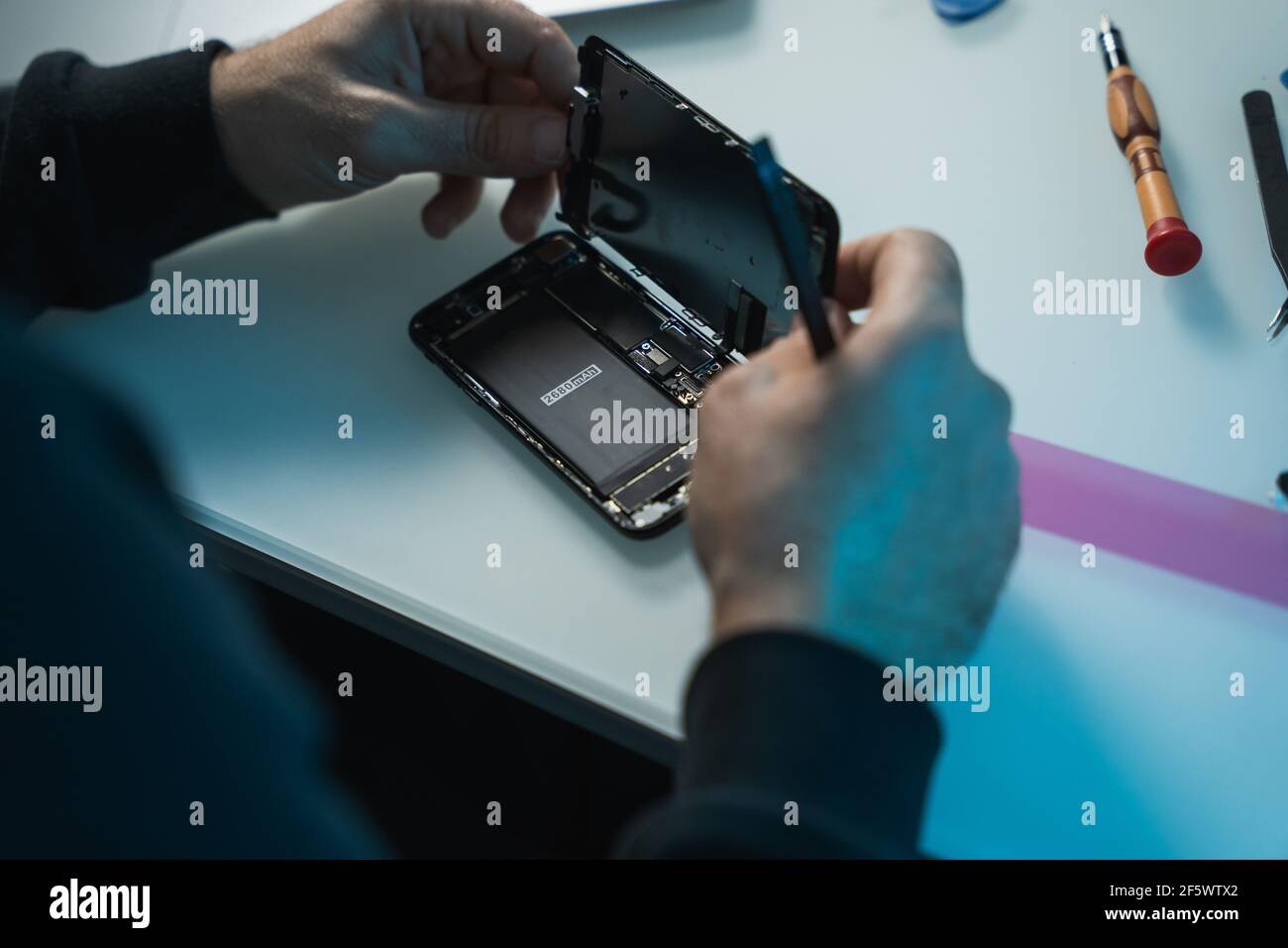 technical man closing the smartphone after installing a new battery ...