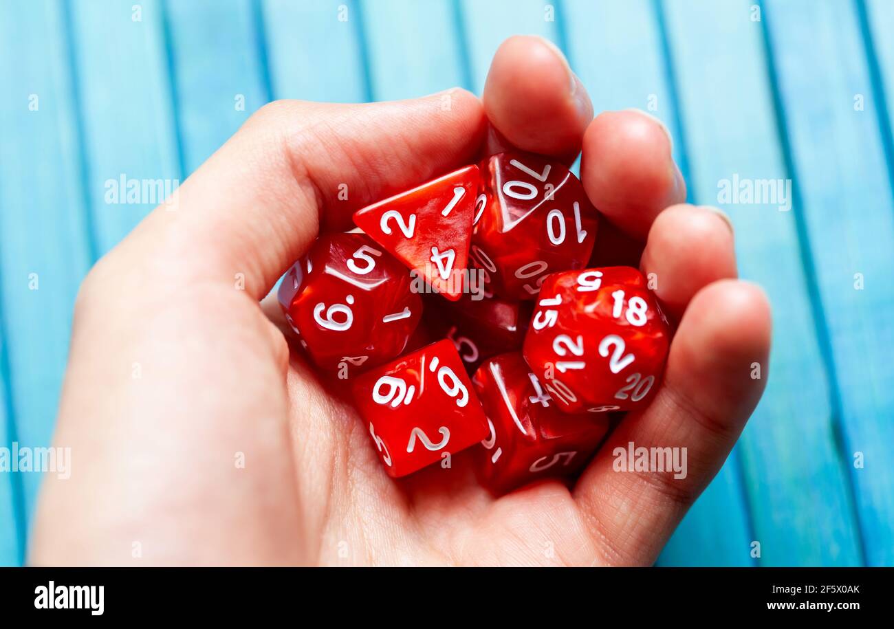 Hand full of red polyhedral RPG board game dice, closeup. Man holding a ...