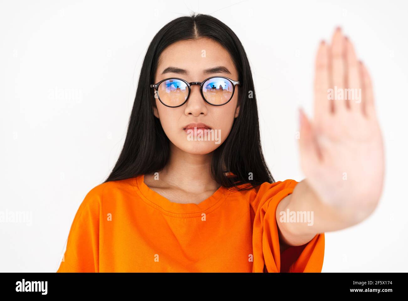Asian serious student girl showing stop gesture at camera isolated over ...