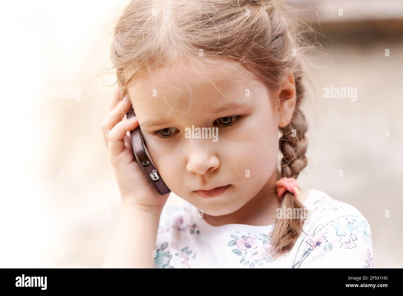 Young child, little school age girl talking on the phone, holding her ...