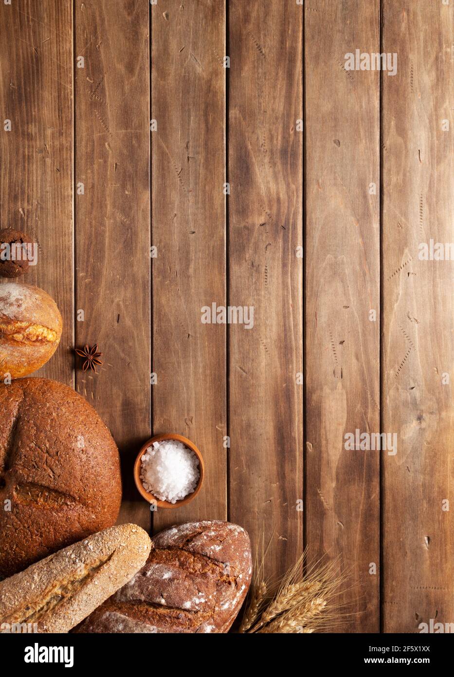 Loaf of fresh bread and buns on wooden table. Assortment of bakery food ...