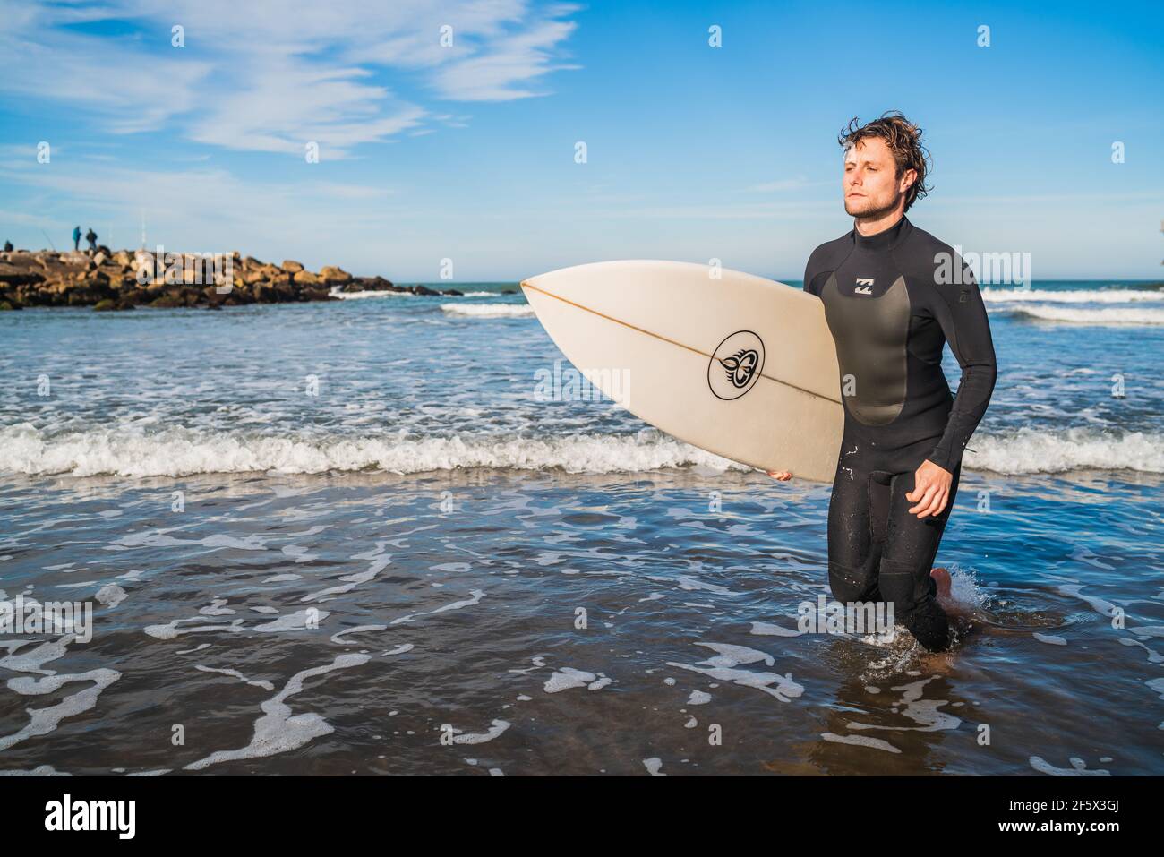 Surfer leaving the water with surfboard under his arm Stock Photo - Alamy