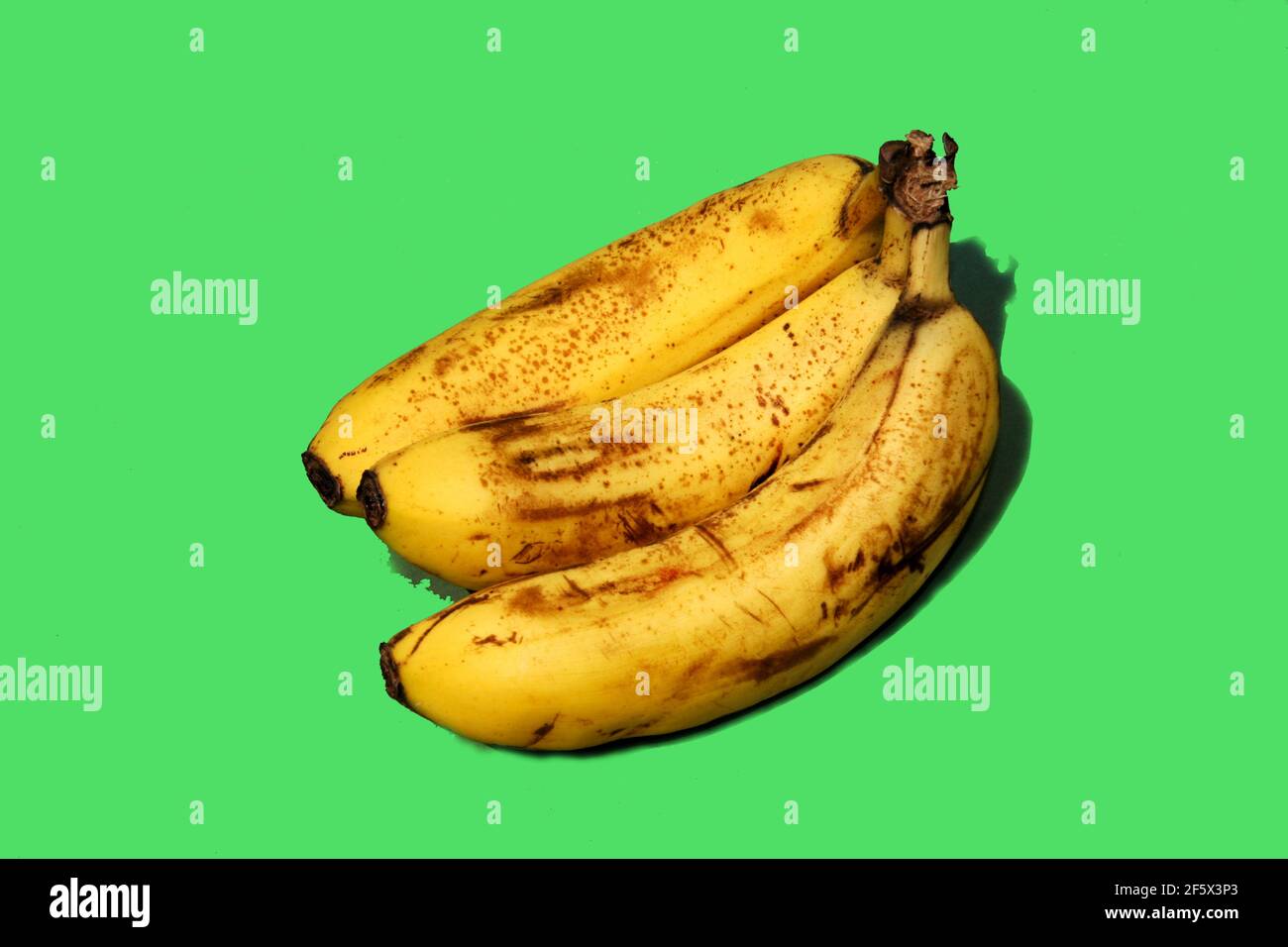 Three ripe bananas isolated in the green background Stock Photo - Alamy