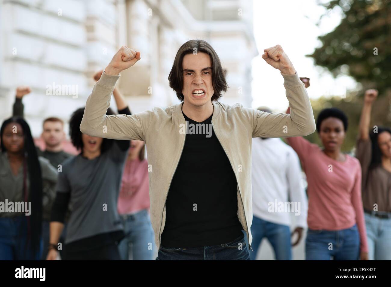 Male activist leading multiracial group of people protesting against ...