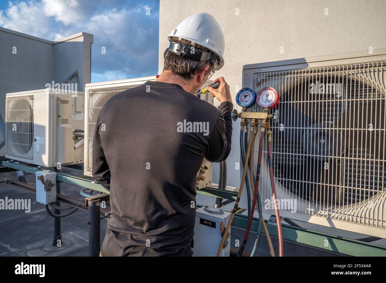 HVAC mechanic using a screw driver to tighten down power terminals to ...