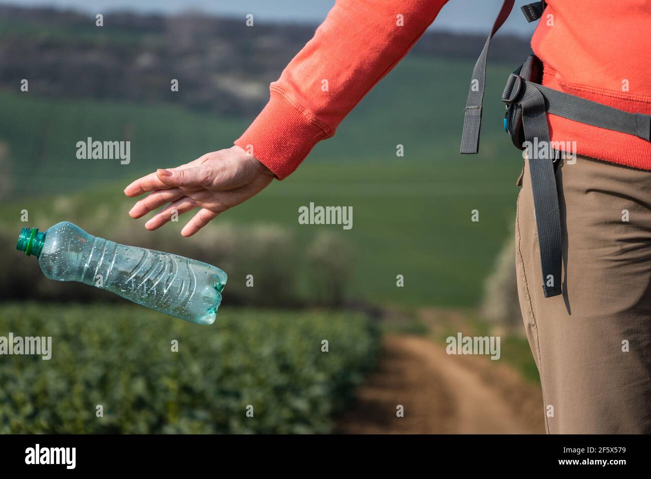Hand throwing away plastic bottle outdoors. Environmental damage by ...