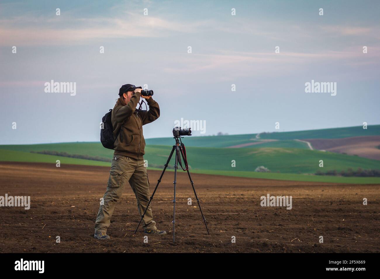 Wildlife photographer looking for animals by binoculars in nature ...