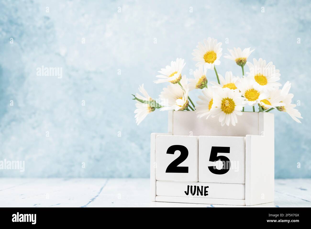 White cube calendar for June decorated with daisy flowers over blue ...