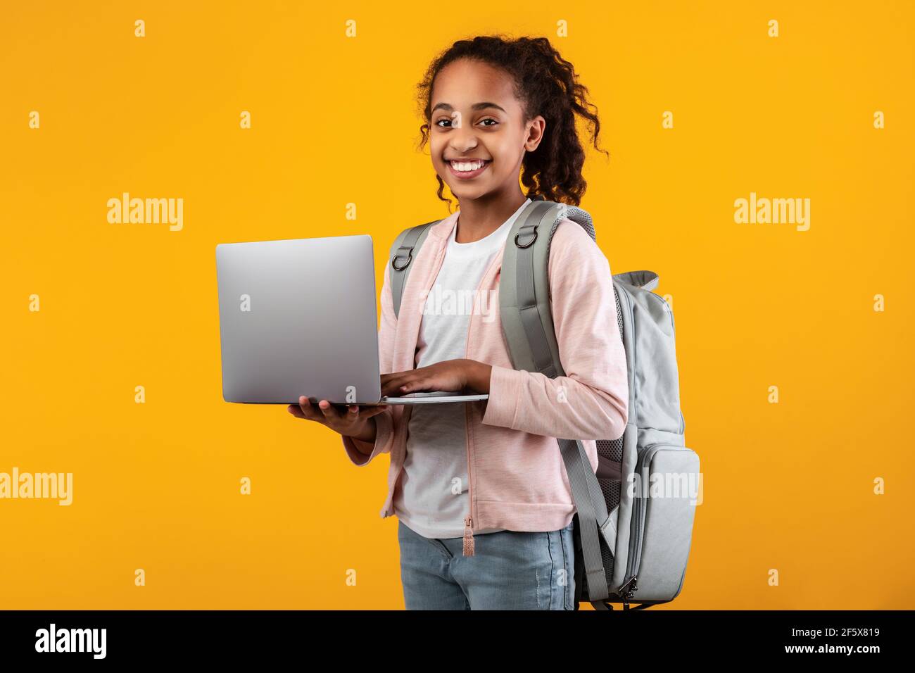Black girl wearing backpack standing with laptop at studio Stock Photo ...