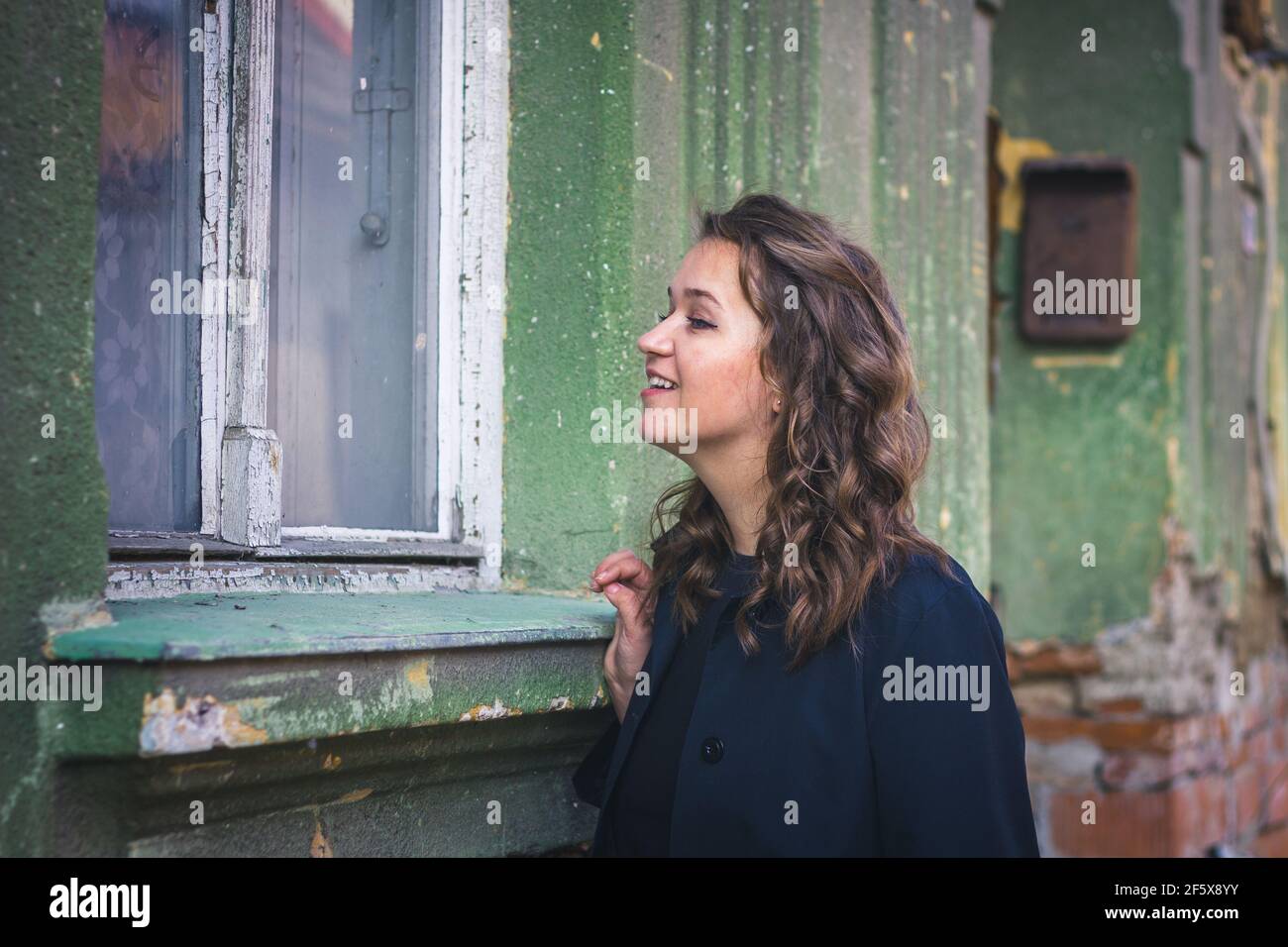 Is anybody home ? Curious woman looking through window to old house in ...