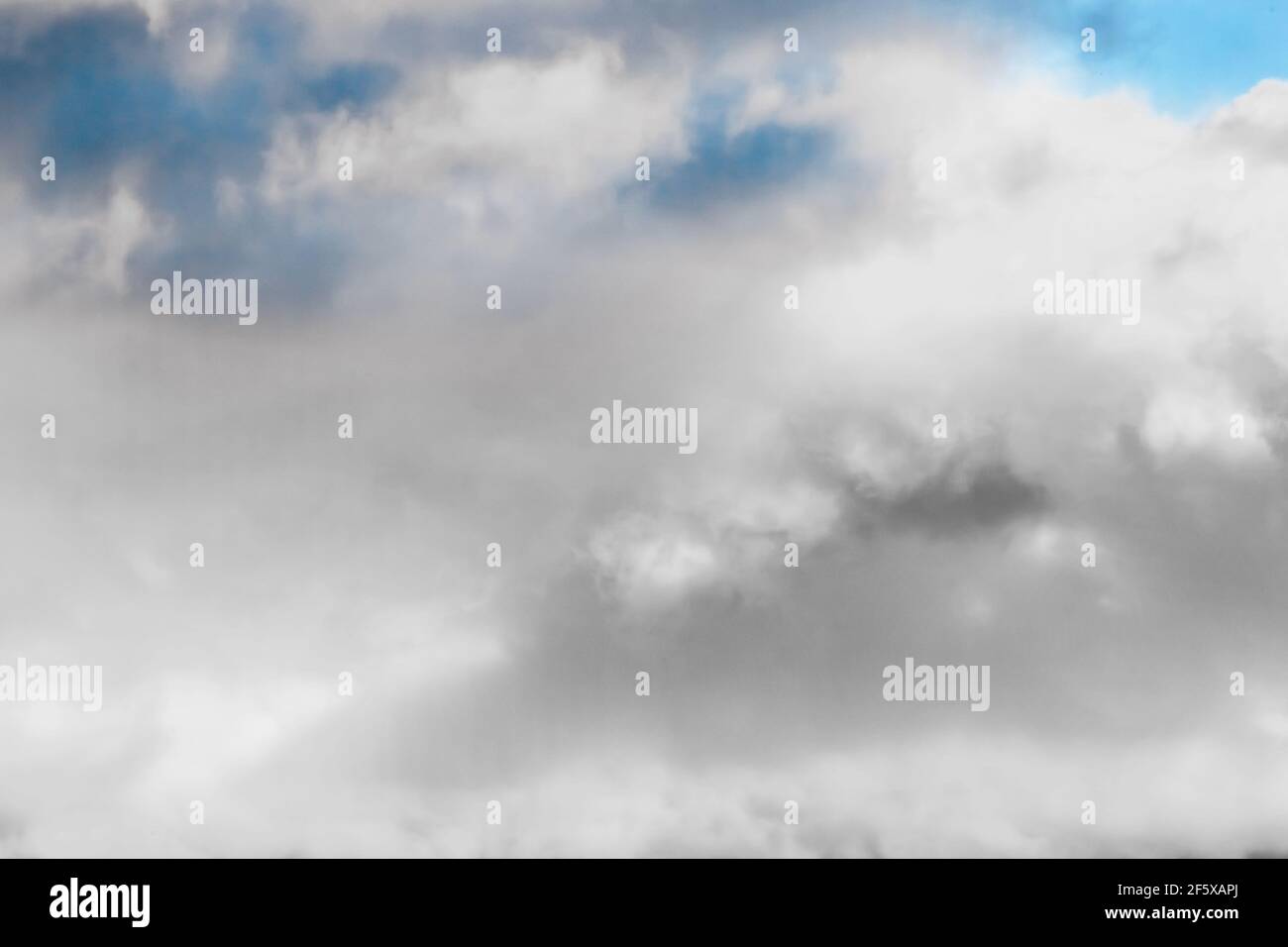 Grey and white rain-dense clouds block the blue sky. Changing weather ...
