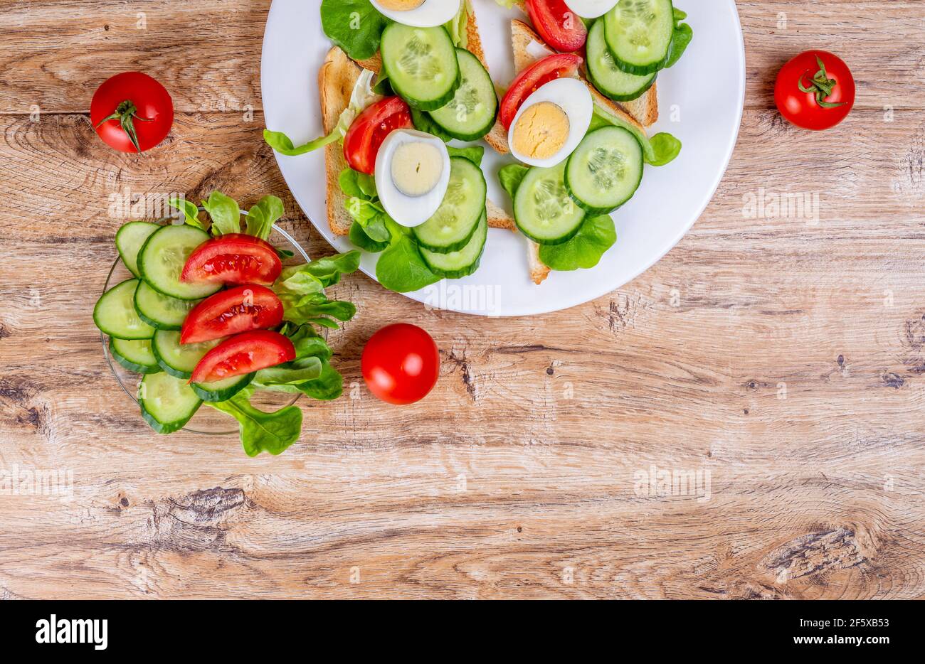 Fried white bread toasts with vegetable and egg slices and cucumber and ...