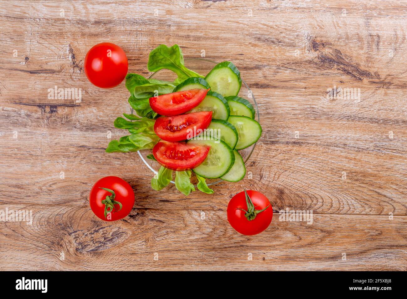 Vegetable slicing of cucumbers and tomatoes on a plate on a wooden ...