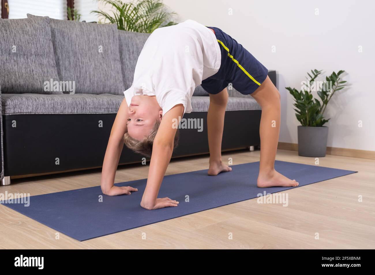 Blond boy goes in for sports on yoga mat. Child physical activity at ...