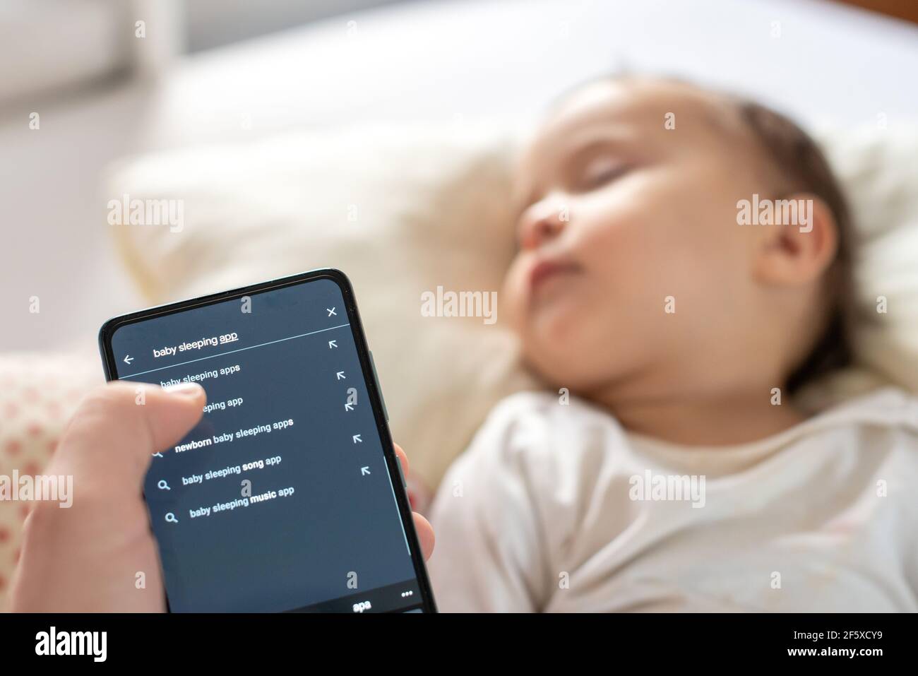 Mom searching the internet using her phone for baby sleeping apps Stock ...