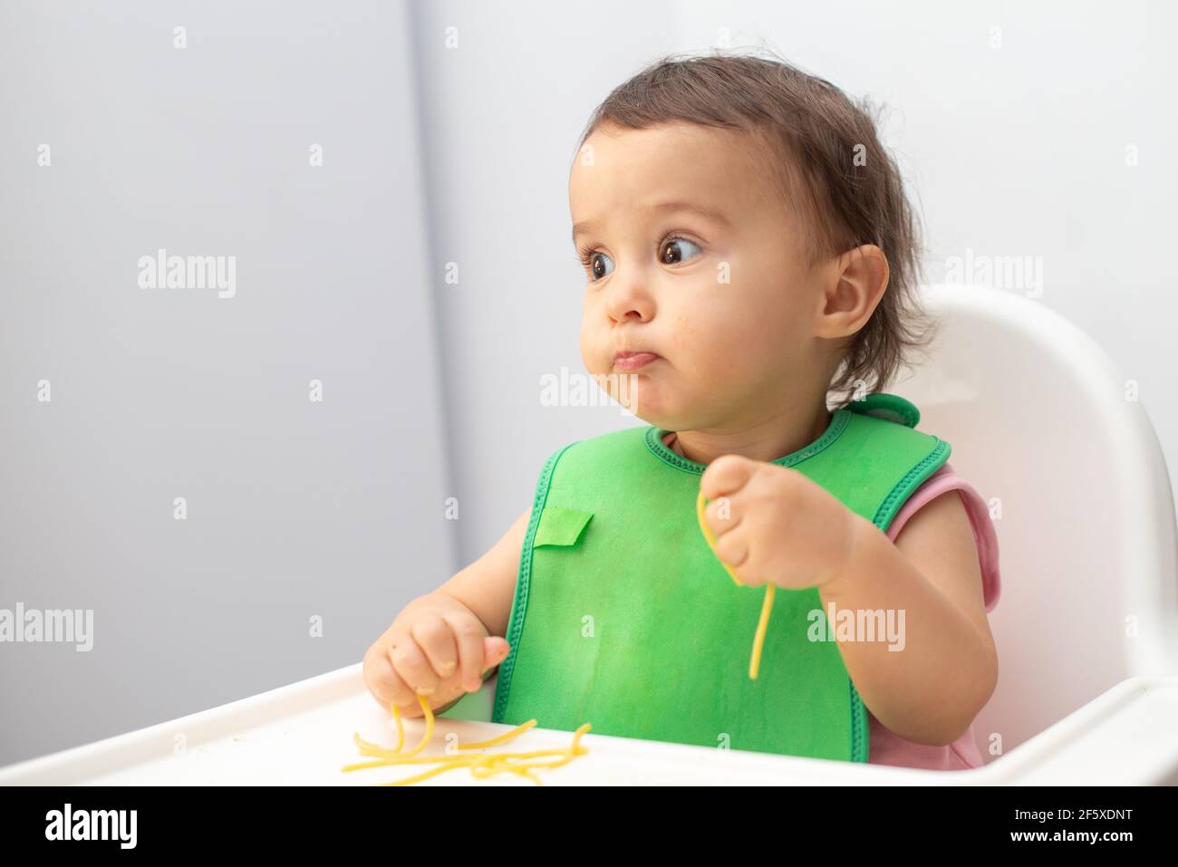 Baby eating pasta in his chair Stock Photo - Alamy