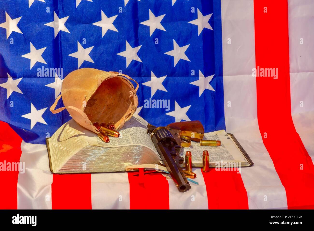 The opened Holy Bible, bull scrotum, bullets, and revolver on the ...