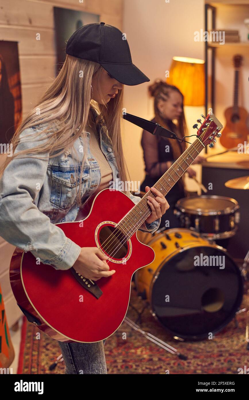 Young female guitarist playing electric guitar with her musical group ...