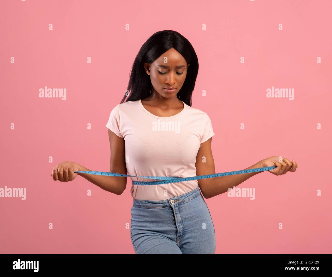 Weight loss. Sad black woman measuring her waist with tape ...
