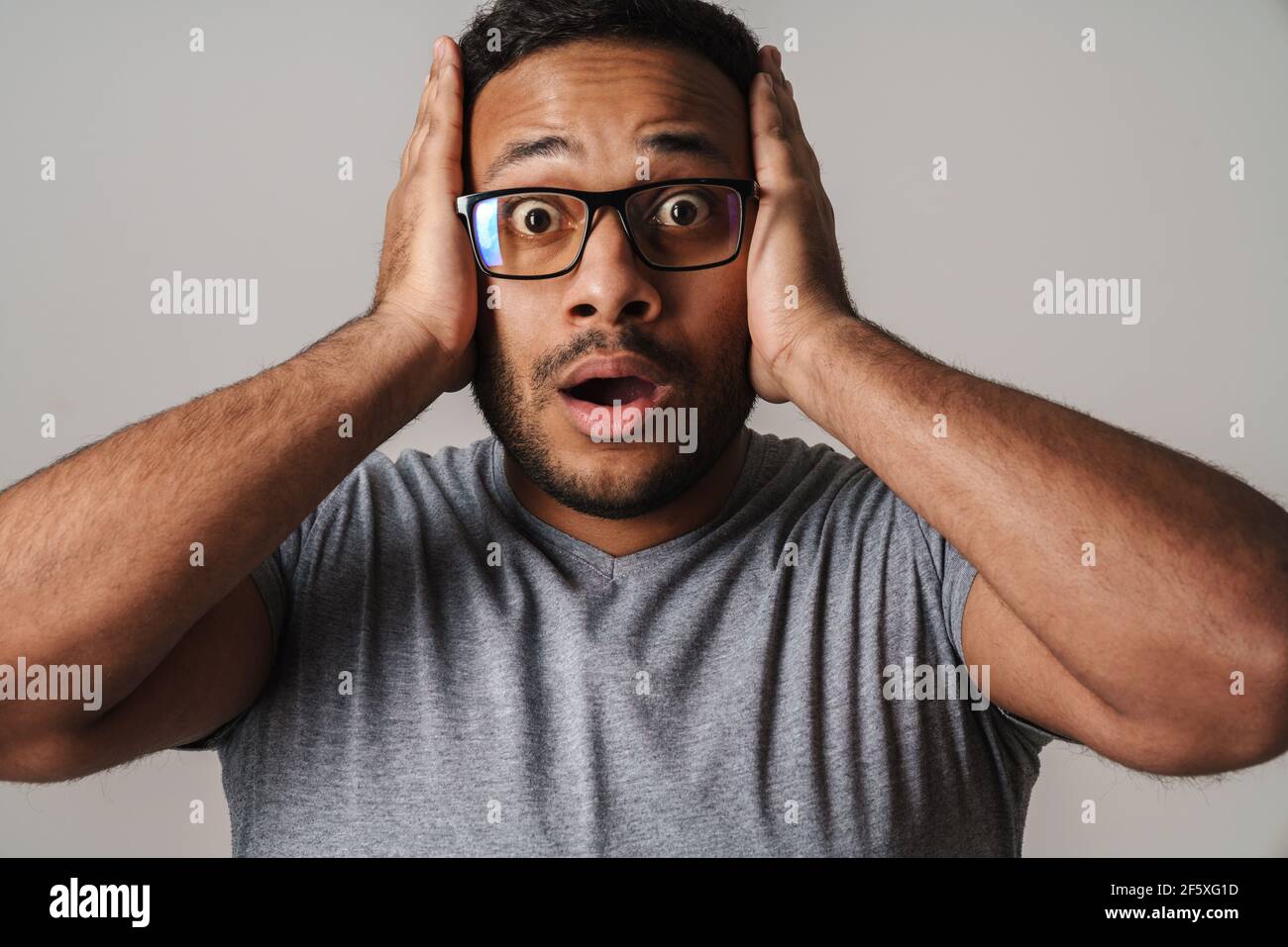 Asian unshaven scared man grabbing his head and looking at camera ...
