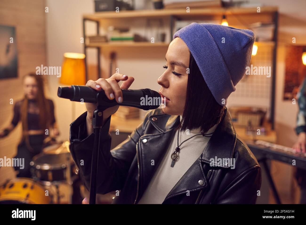 Female singer singing in microphone and rehearsing with her colleagues ...