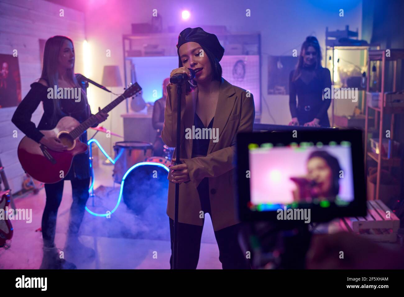 Singer singing in microphone while her group playing on musical ...