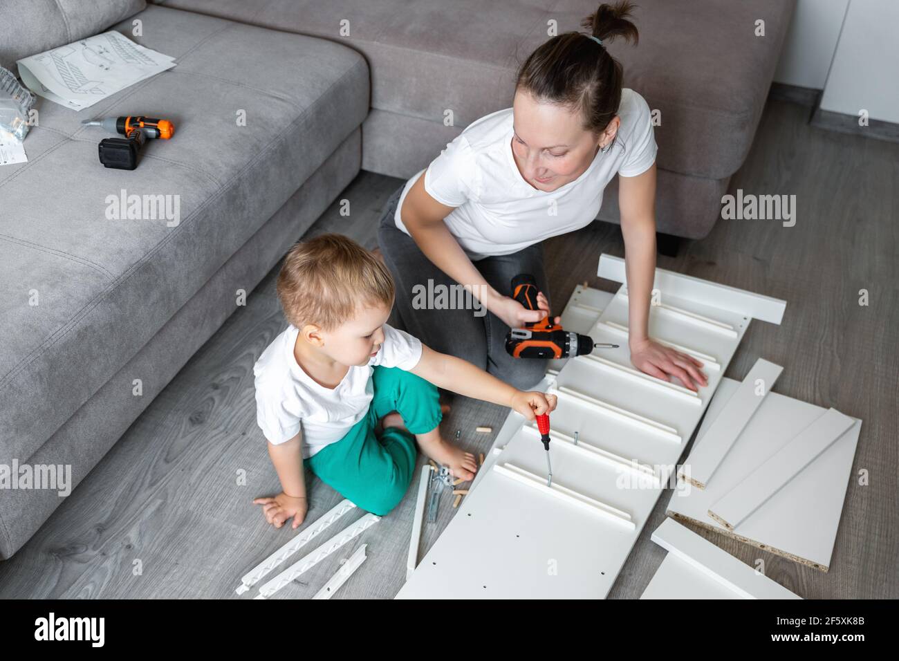 Cute adorable caucasian toddler boy kid sit on floor and help mom ...