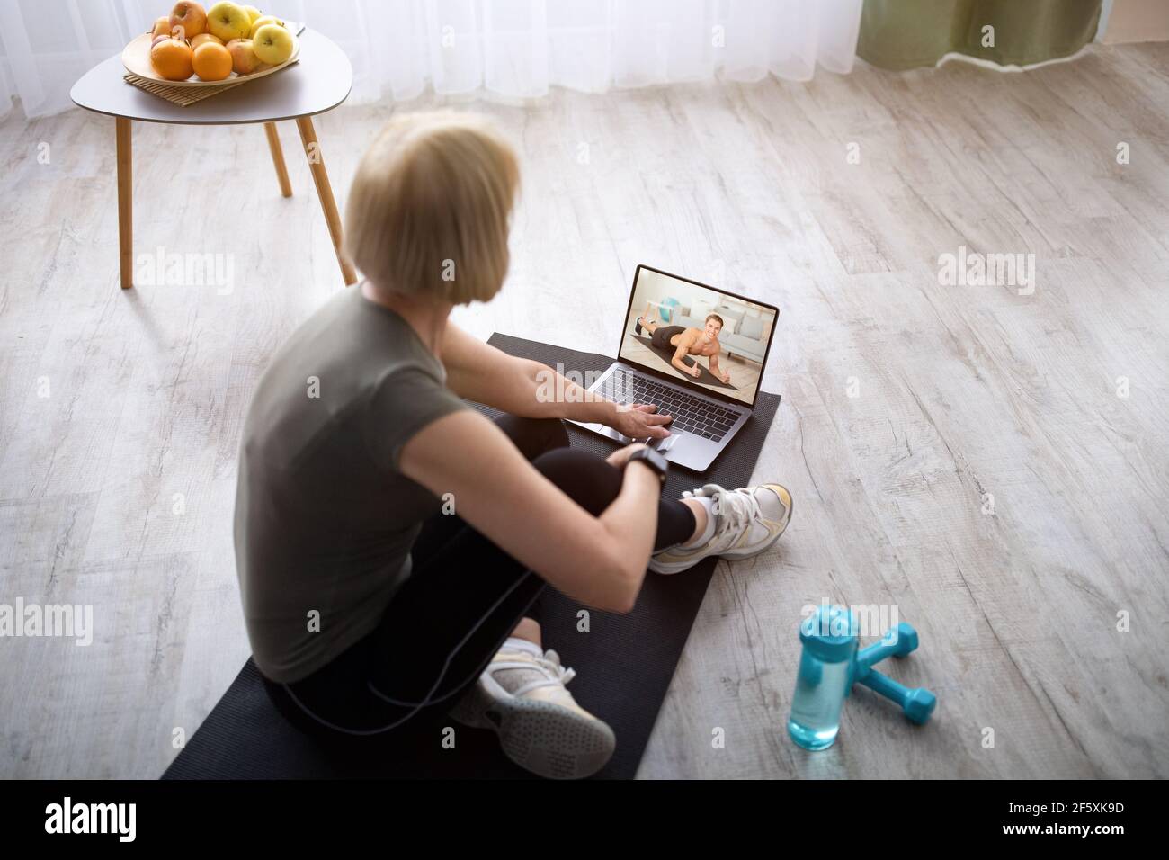 Senior woman watching online video sports tutorial on laptop, taking ...