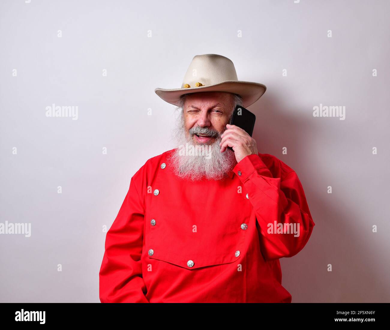 Old rancher in red western bib shirt using his cellphone Stock Photo ...