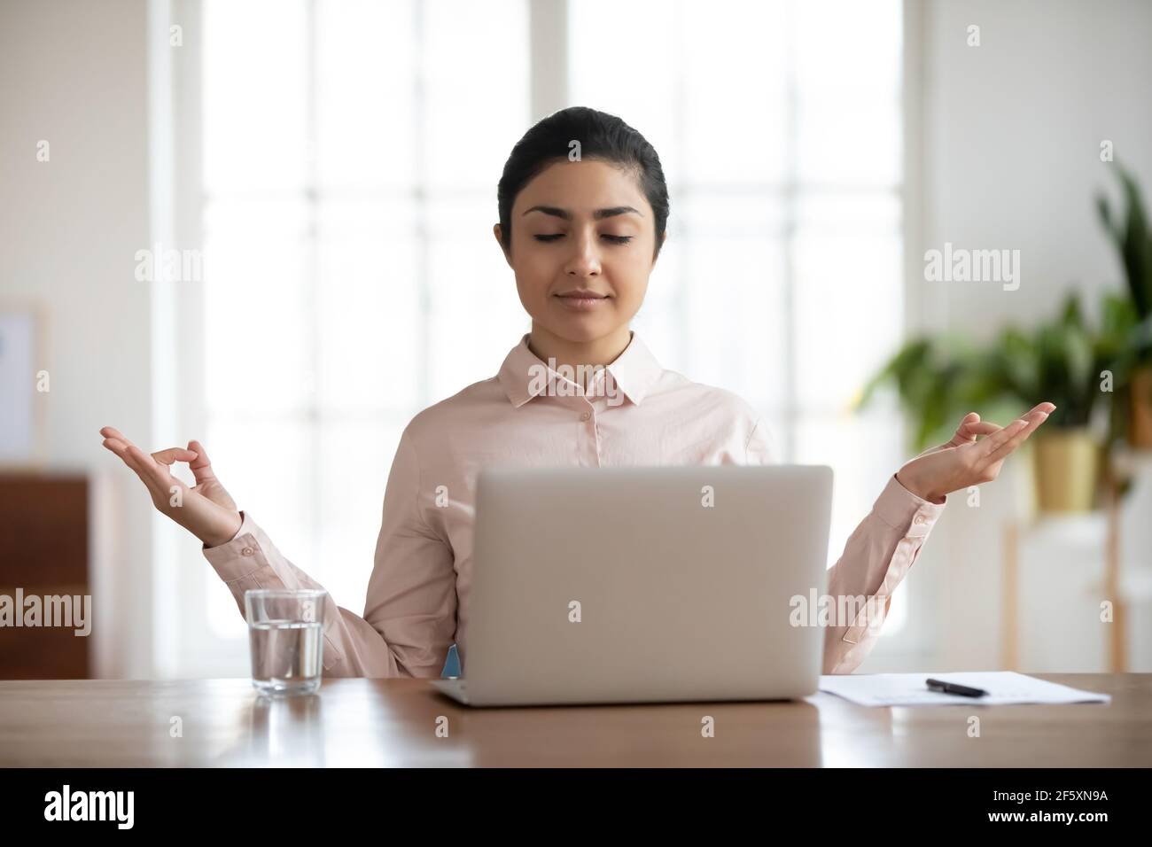 Calm Indian woman distracted from computer work meditating Stock Photo ...