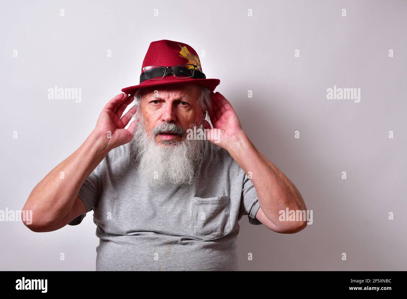 An old American male with grey shirt and red fedora hat indicating he ...