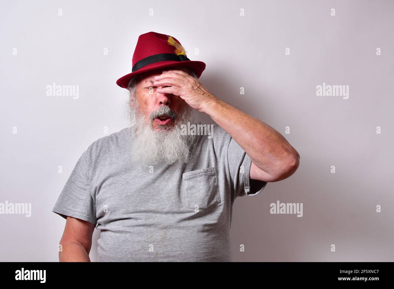 A shocked American male with a grey shirt and red fedora hat on white ...