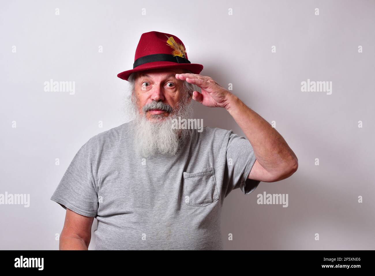 An old American male with a grey shirt and red fedora hat saluting ...