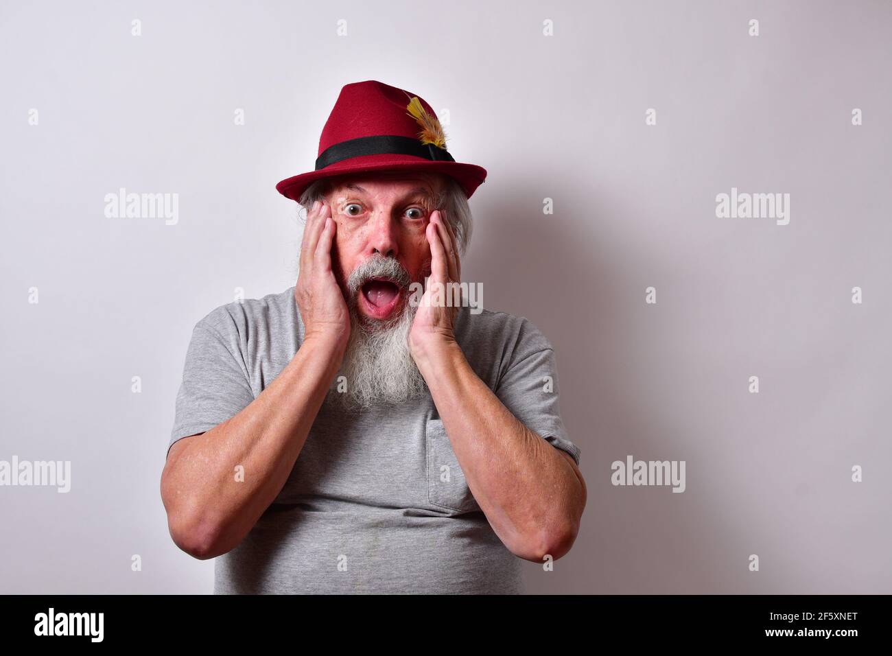 A shocked American male with a grey shirt and red fedora hat on white ...
