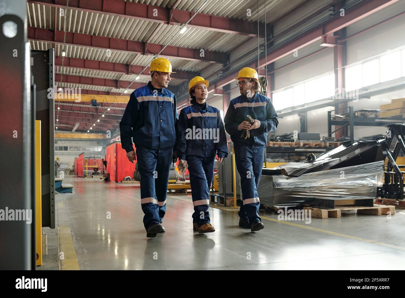 Group of workers or engineers of contemporary industrial plant moving ...