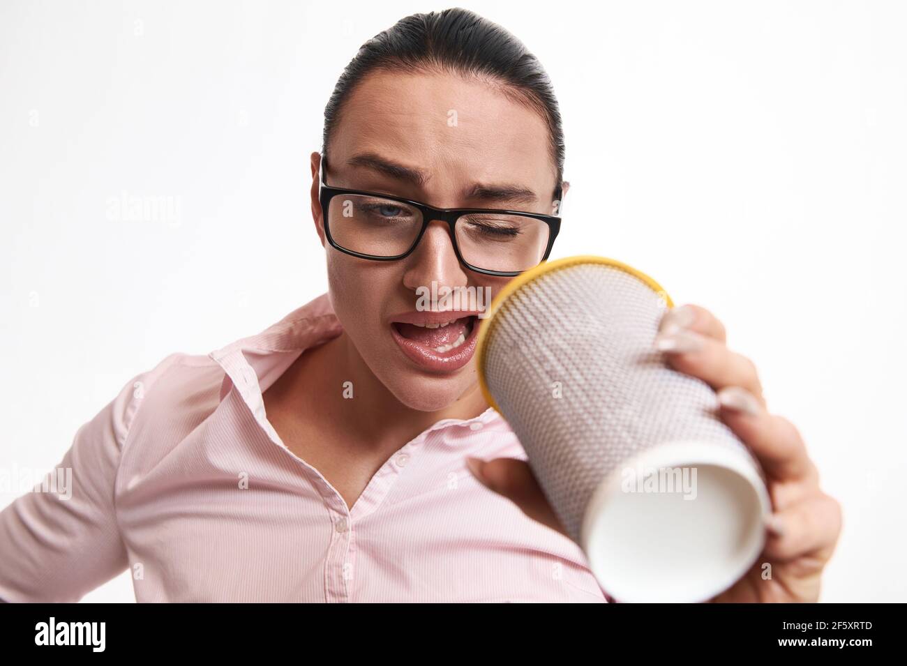 Confused woman in eyeglasses looking through takeaway paper cup ...