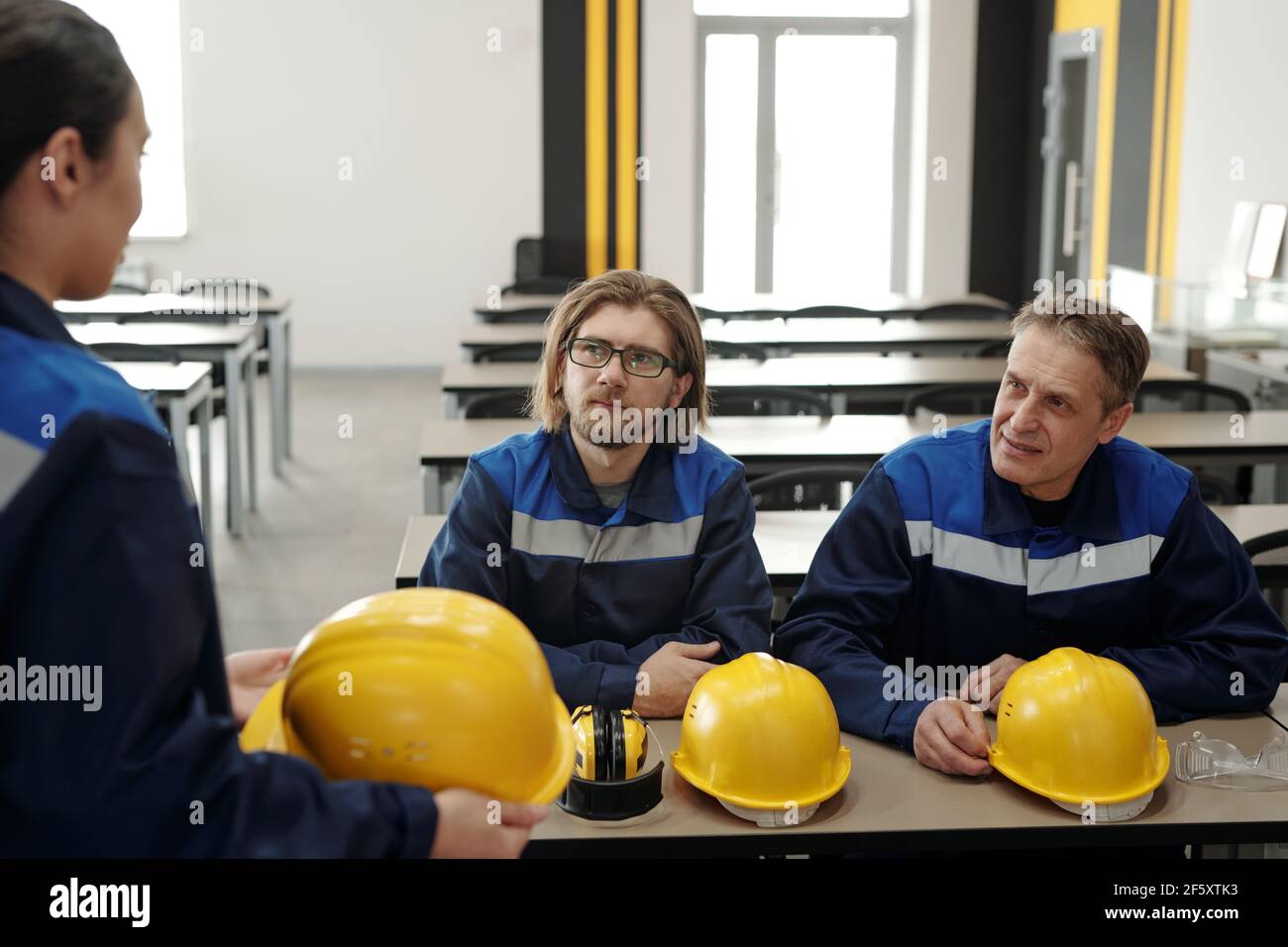 Two male workers of industrial plant sitting by one of desks in ...